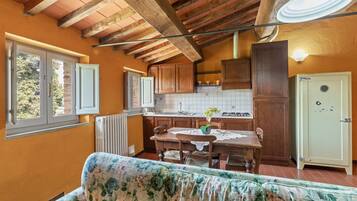Cozinha acolhedora com armários de madeira, uma mesa de jantar e um radiador.