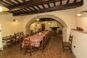 Uma sala de jantar com uma mesa comprida, cadeiras de madeira e uma lareira de tijolos.