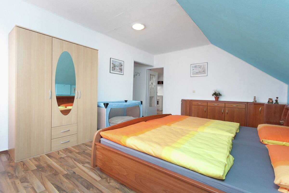 Quarto com cama de madeira, guarda-roupa com espelho e teto azul.