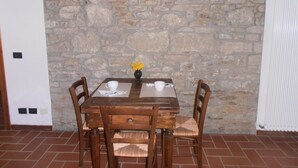 Paredes de pedra com uma mesa de madeira e quatro cadeiras.