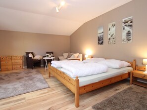 Quarto com cama de madeira, escrivaninha, cadeira, cômoda e arte nas paredes.