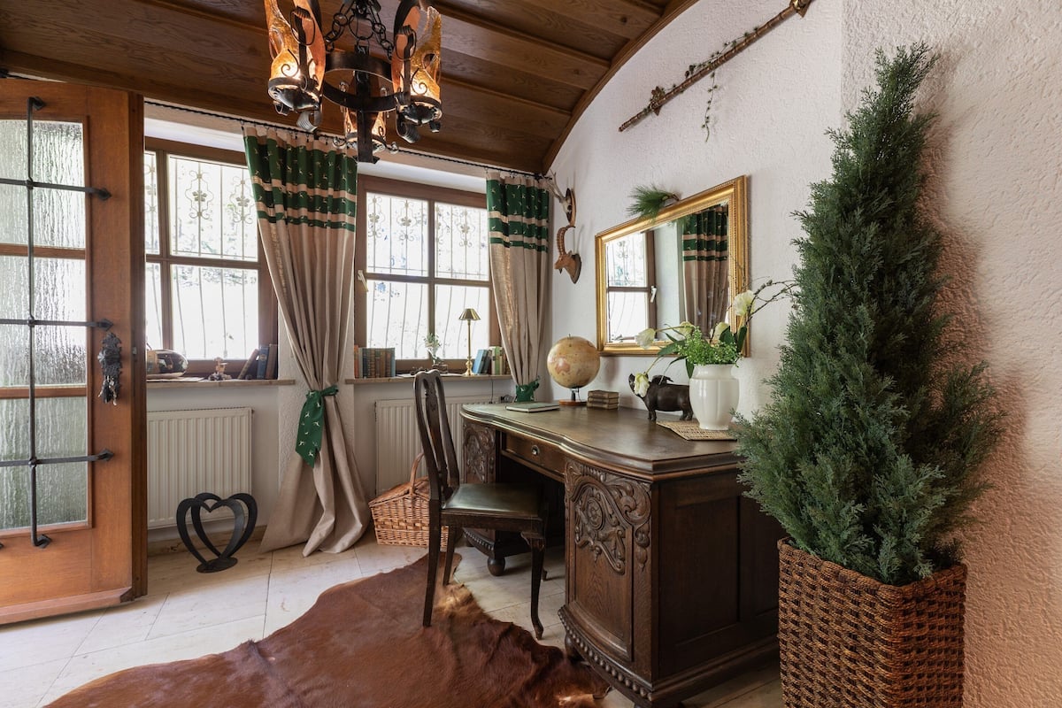 Um quarto aconchegante com uma escrivaninha de madeira, um globo, um espelho e uma planta em vaso.