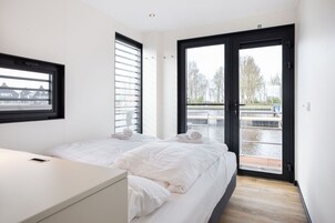 Quarto de hotel moderno com duas camas, uma escrivaninha e uma grande janela com vista para a água.