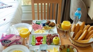 Uma mesa de pequeno-almoço com vários pratos, incluindo ovos, carnes, frutas e pão.