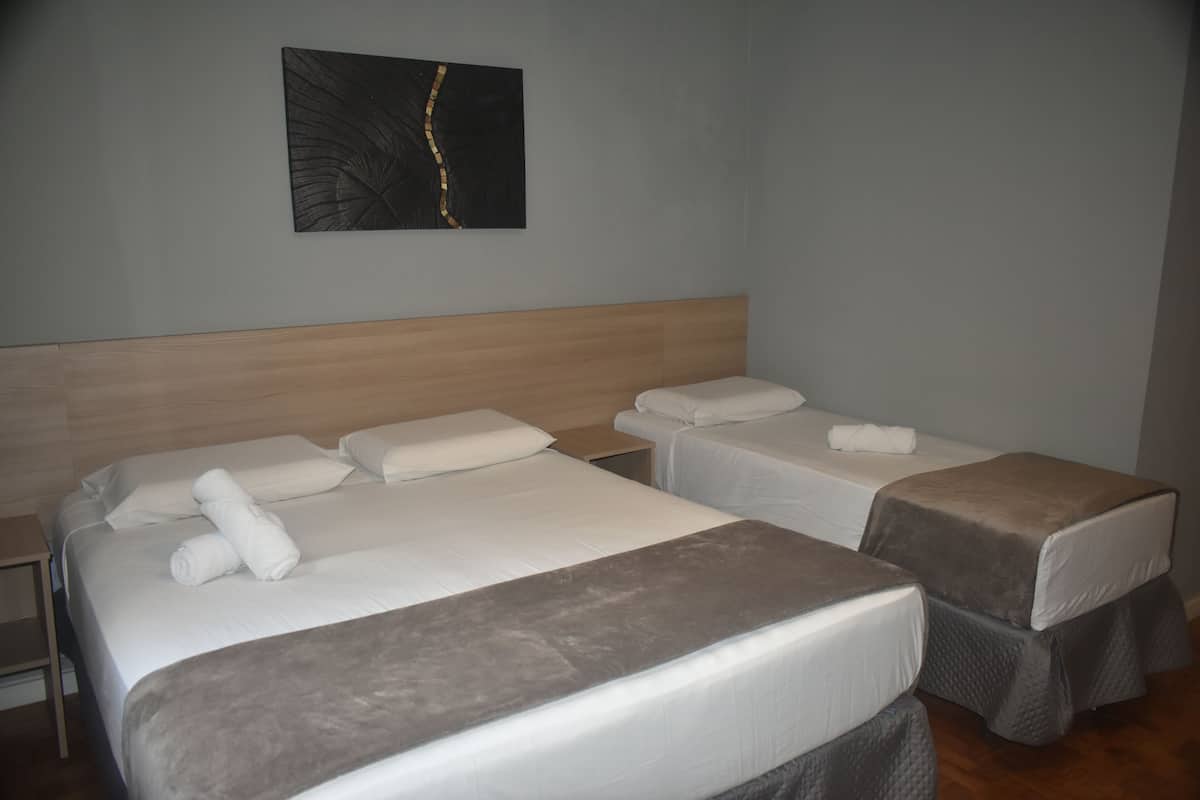 Quarto de hotel com duas camas, cabeceira de madeira e uma obra de arte pendurada na parede.