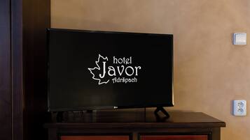 Uma televisão de tela plana sobre uma cômoda de madeira, exibindo o logotipo de 'hotel Javor' e 'Narspace' na tela.