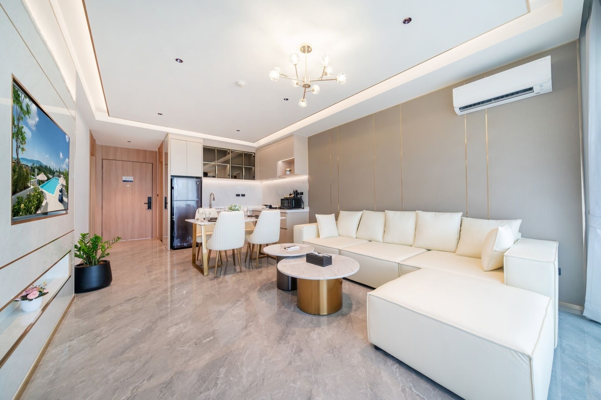 Uma sala de estar moderna com um sofá branco, duas mesas de centro redondas e um espaço de jantar com cadeiras brancas.