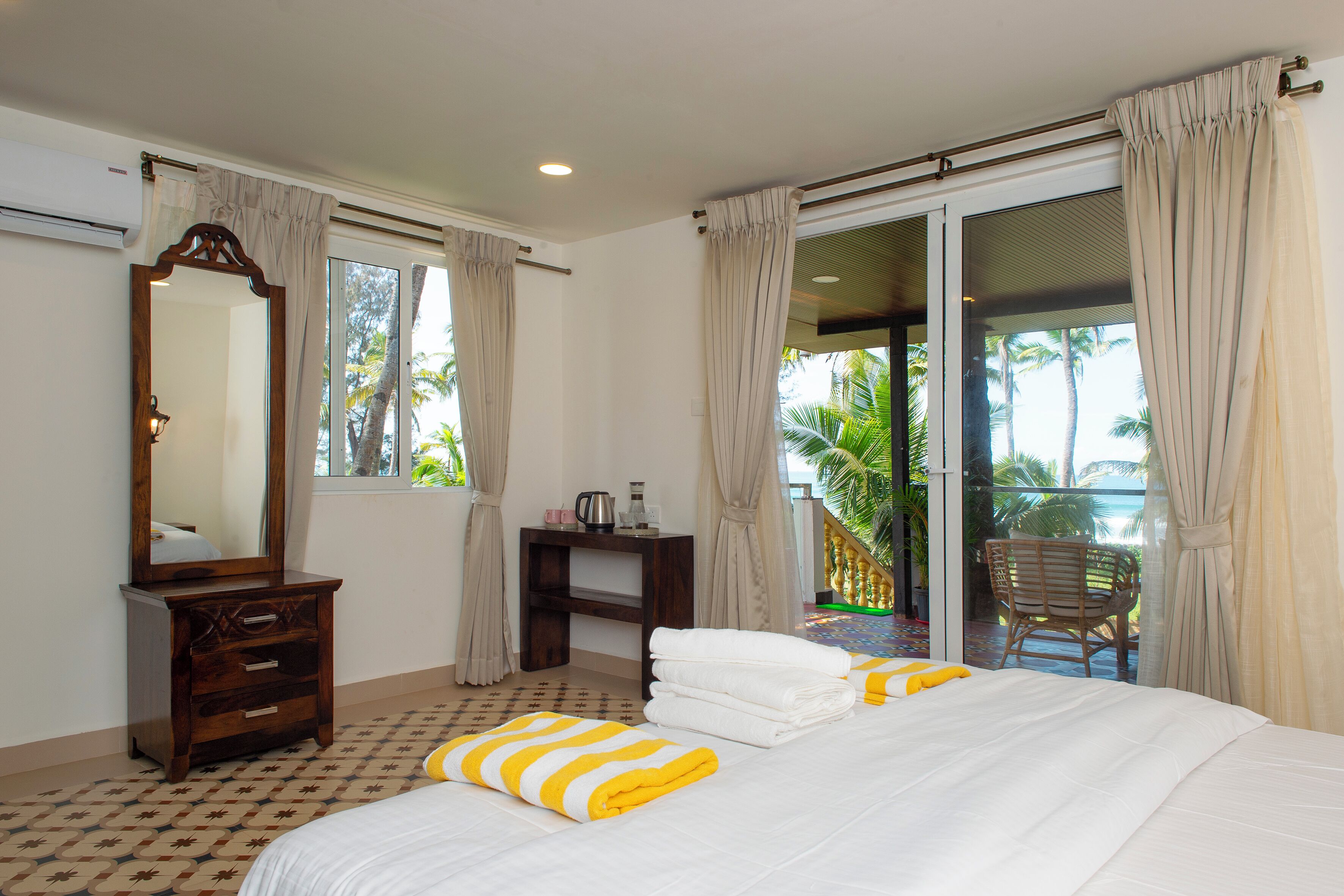 Quarto de hotel com cama, penteadeira, espelho, mesinha e cadeira.