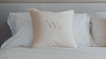 Cama com cabeceira e almofadas, uma delas com monograma.