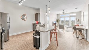 Uma cozinha moderna com ilha central, eletrodomésticos de aço inoxidável e área de jantar com mesa e cadeiras.