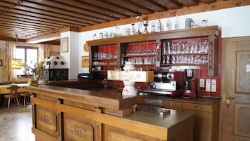 Uma cozinha com armários de madeira, uma máquina de café e uma estante com copos.