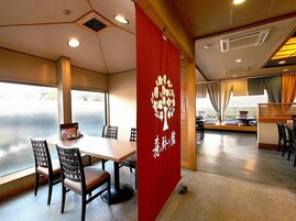 Um restaurante com uma janela grande, um letreiro vermelho com caracteres chineses e uma mesa com cadeiras.