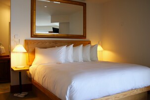 Uma cama bem arrumada com lençóis brancos e duas luminárias de cabeceira.