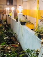 Um espaço ao ar livre estreito, com plantas em vasos e uma parede de concreto.
