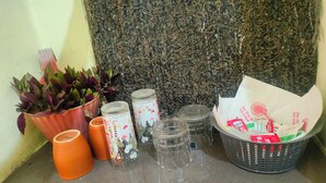 Uma bancada com uma planta em vaso, dois vasos laranja, um cesto de saquinhos de chá e vários potes de vidro.
