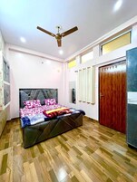 Quarto com cama, ventoinha no teto, guarda-roupa e janela.