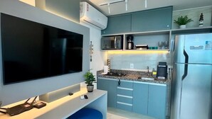 Cozinha moderna com televisão de tela plana, eletrodomésticos embutidos e banquetas azuis.