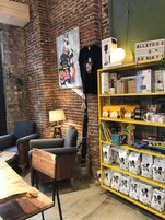 Um café acolhedor com paredes de tijolo, uma mesa de centro de madeira e uma prateleira com produtos de café.