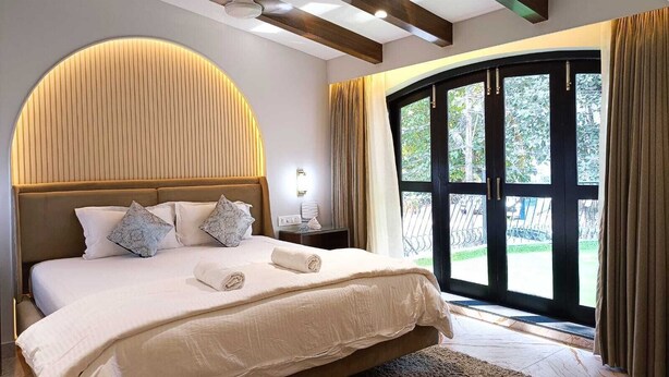 Um quarto espaçoso com uma cama grande, design de parede curva, ventilador de teto e vista pela janela.