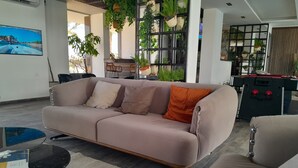 Uma sala de estar moderna com um sofá bege, uma mesa de centro e uma TV fixada na parede.