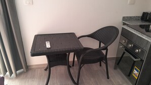 Uma cozinha compacta com um fogão preto, uma mesa pequena e duas cadeiras de vime.