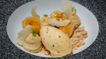 Prato de sobremesa com sorvete, fruta e crumble em bancada salpicada.