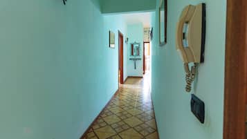 Um corredor com ladrilhos estampados no chão, paredes azul claro e um telefone na parede.