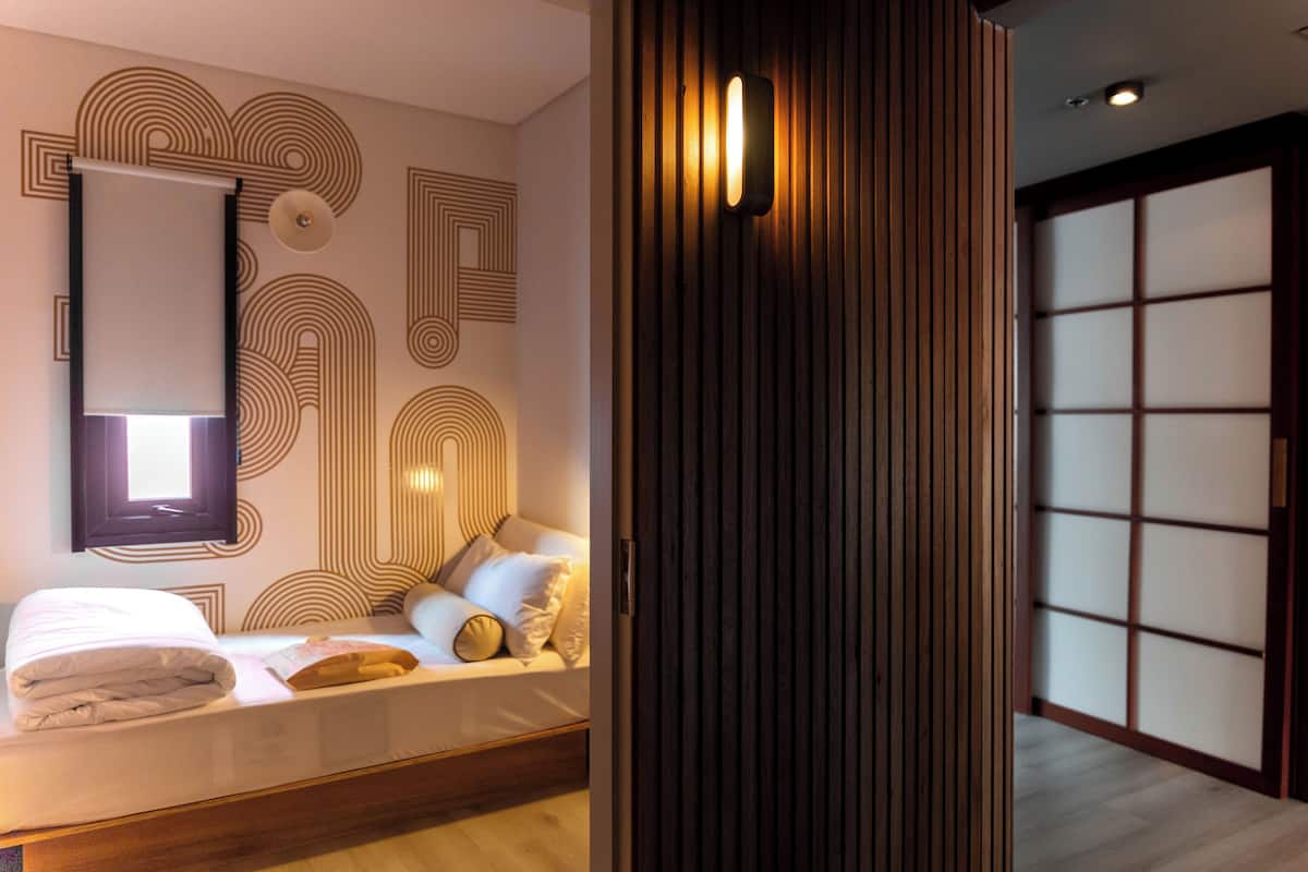 Quarto de hotel moderno com cama, um espelho grande e um design geométrico na parede.