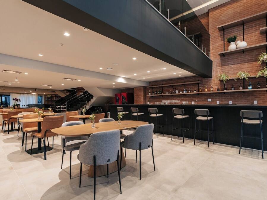 Uma área de bar moderna com parede de tijolos, banquetas e diversas garrafas.