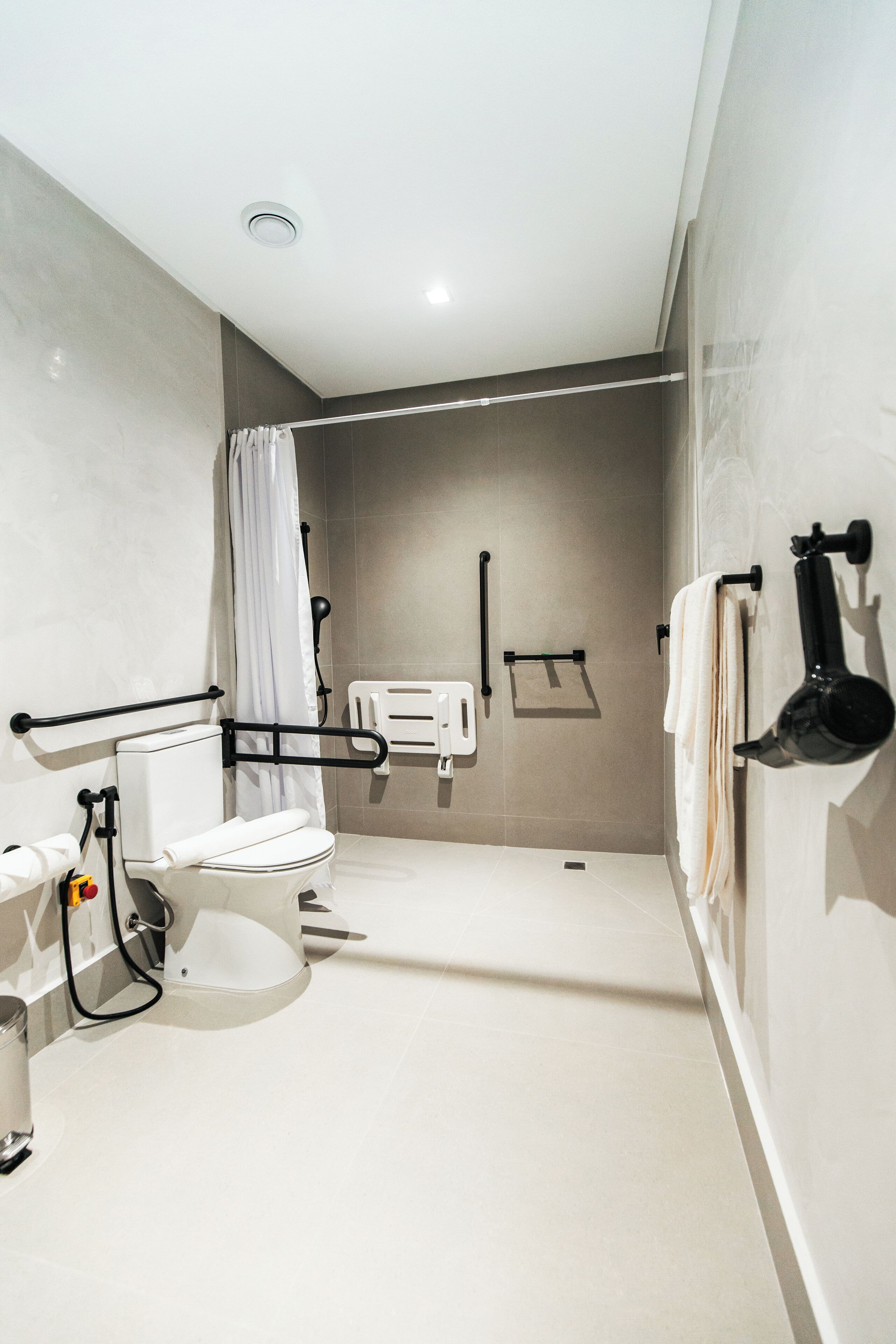 Uma casa de banho moderna com sanita, chuveiro e secador de mãos.