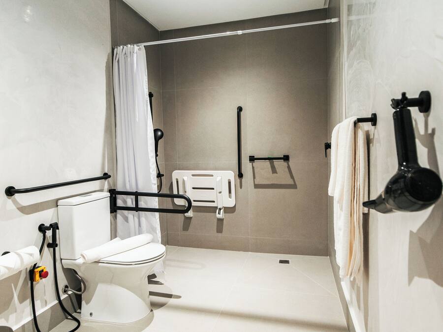 Uma casa de banho moderna com sanita, chuveiro e secador de mãos.