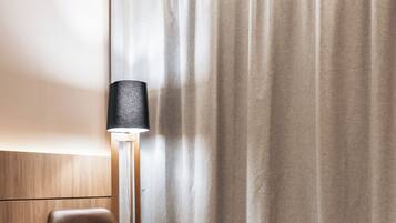 Quarto moderno com poltrona de couro, mesa redonda de madeira e luminária de chão.