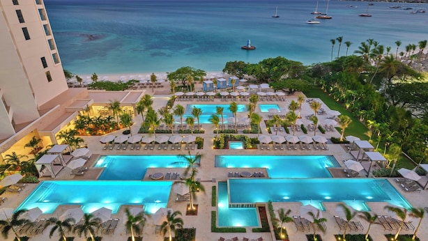Um resort com várias piscinas, áreas de estar e vista para o mar.