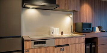 Uma cozinha moderna com forno embutido, cuba de aço inoxidável e micro-ondas.