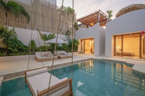 Uma área de piscina moderna com espreguiçadeiras, um painel de bambu e interior bem iluminado.