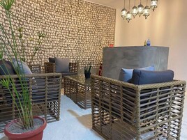 Quarto com móveis de vime, parede de pedra e luminária pendente.