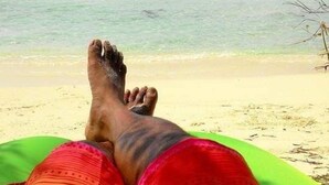 Uma pessoa deitada na praia, com vista para o oceano.