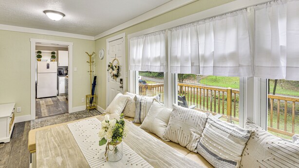 Um quarto aconchegante com uma janela grande, um banco com almofadas e vista para um deck.