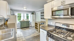 Uma cozinha moderna com eletrodomésticos de aço inoxidável, micro-ondas embutido e fogão a gás.