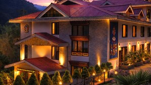 Um hotel com estilo arquitetônico tradicional, destacando uma entrada imponente, várias janelas e uma fachada bem iluminada.