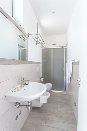 Quarto quádruplo conforto | Banheiro | Chuveiro, toalhas de banho, sabonete, shampoo