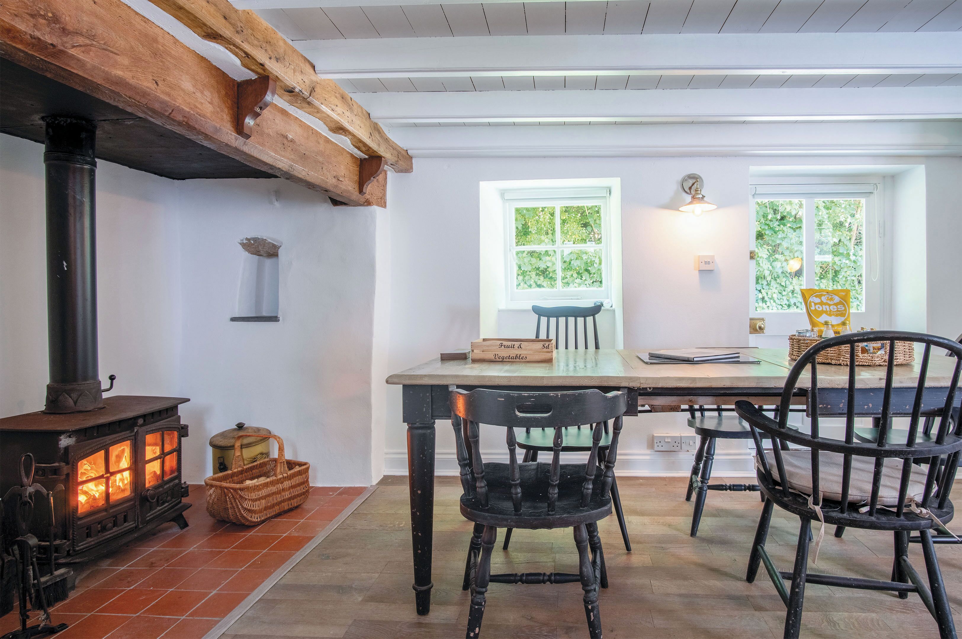 Uma área de jantar acolhedora com um fogão rústico, cadeiras de madeira e uma mesa posta para refeição.