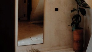 Um corredor com um espelho grande em arco, um vaso de planta e duas luminárias de vime suspensas.