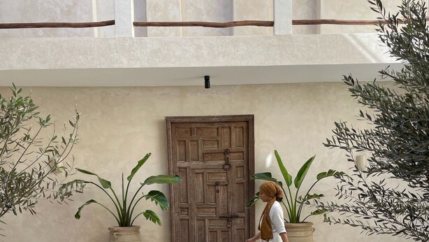 Área de piscina com porta de madeira, plantas em vasos e espreguiçadeiras.