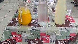 Uma mesa comprida posta com diversos copos e garrafas, provavelmente para uma refeição ou evento.
