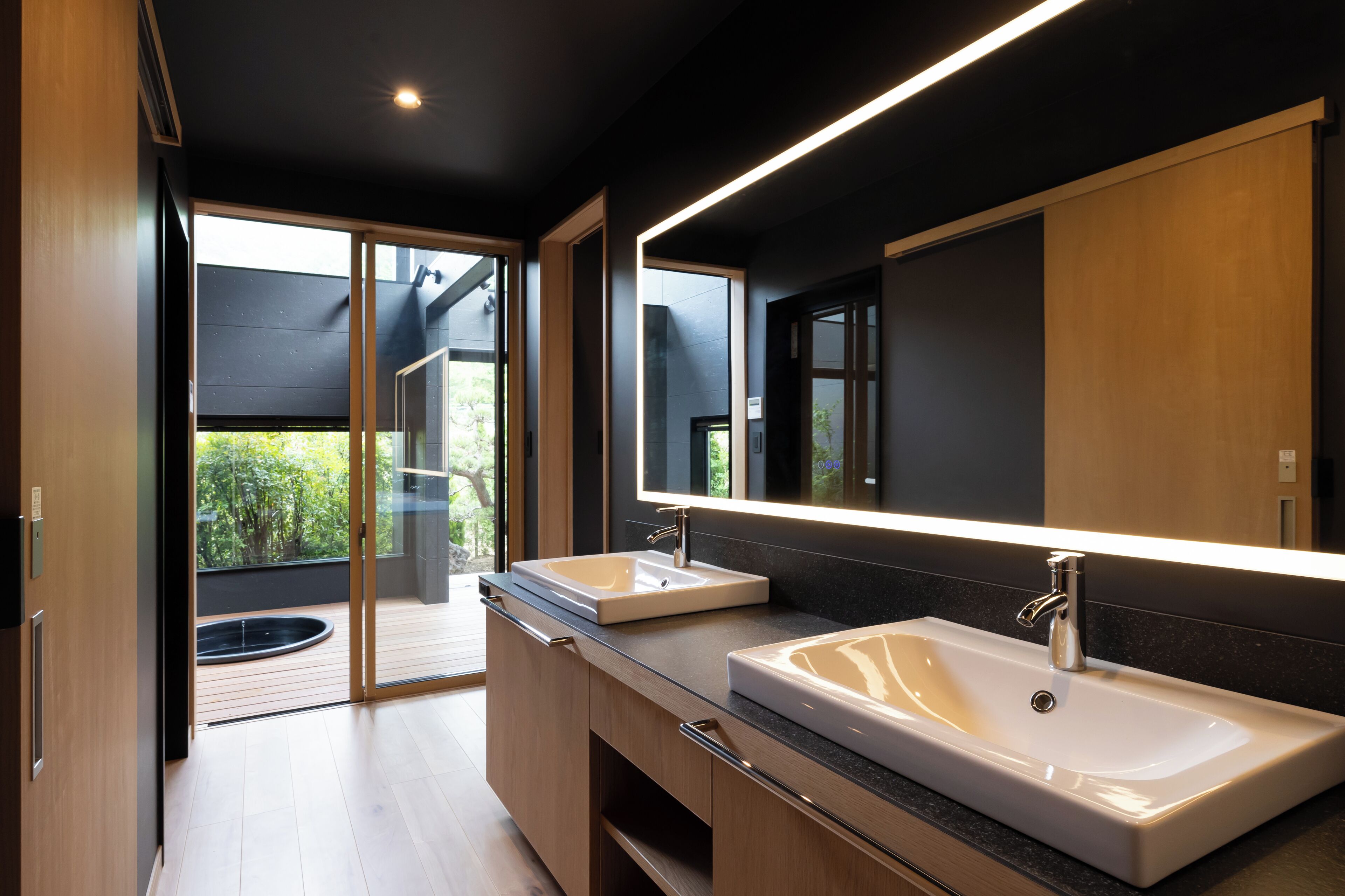 Uma casa de banho moderna com duas pias, um espelho grande e uma porta de vidro deslizante para uma varanda.