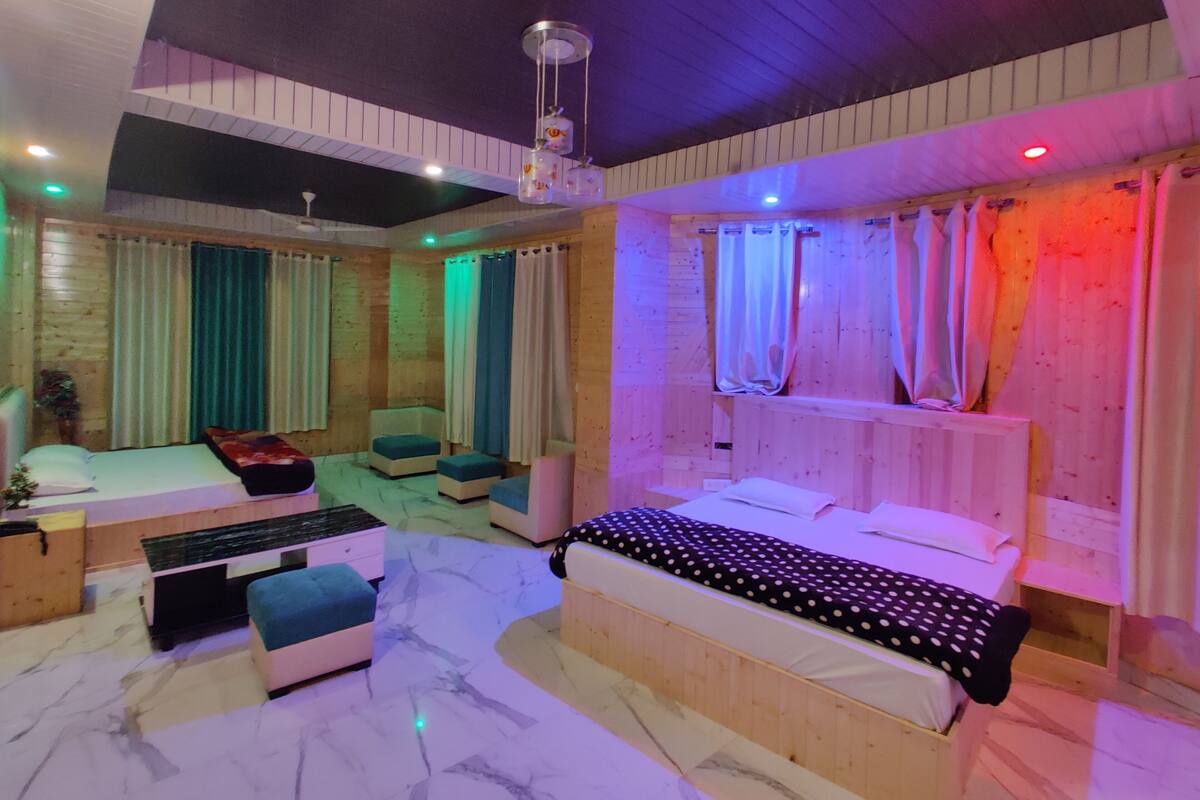 Quarto com cama, duas áreas de estar e luminária no teto.