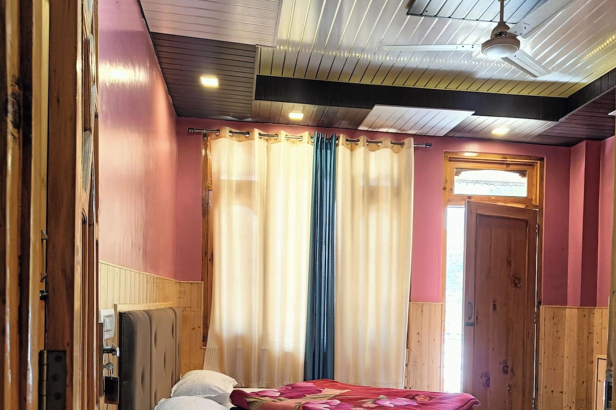 Quarto com cama, cabeceira de madeira, cortinas e ventilador de teto.