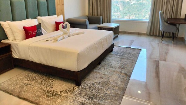 Quarto de hotel moderno com uma cama grande, uma mesa de trabalho e vista para o exterior.