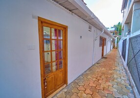 Um corredor estreito com piso de azulejos e porta de madeira com painéis de vidro.